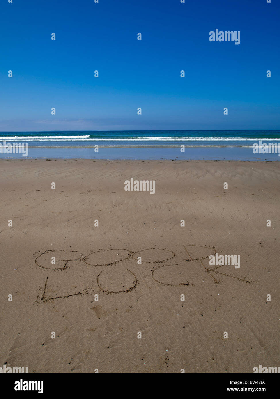 writing in the sand on a beach with the sea in the distance and a blue ...