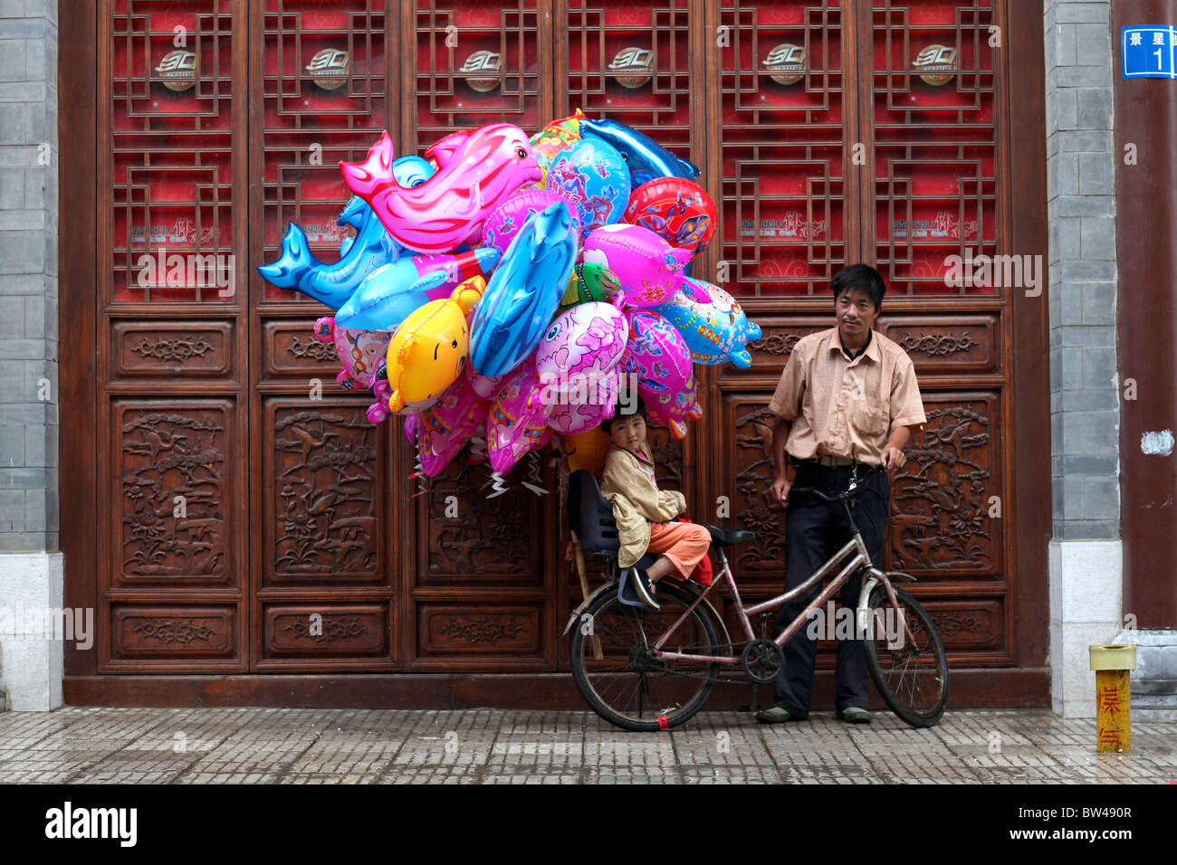 A balloon salesman standing by traditional chinese wooden doors in ...