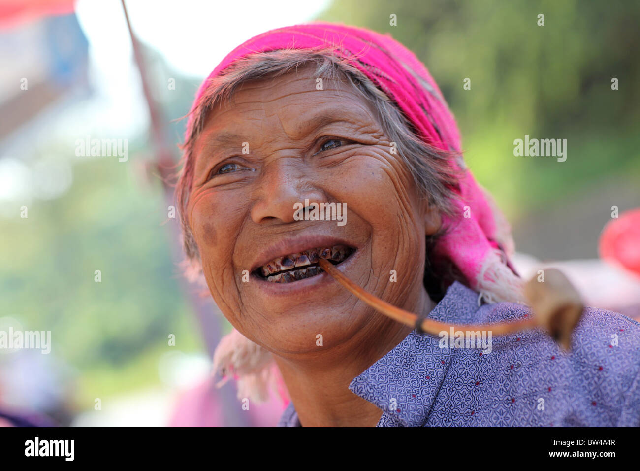 A woman belonging to the Dai minority ethnic group smoking a ...