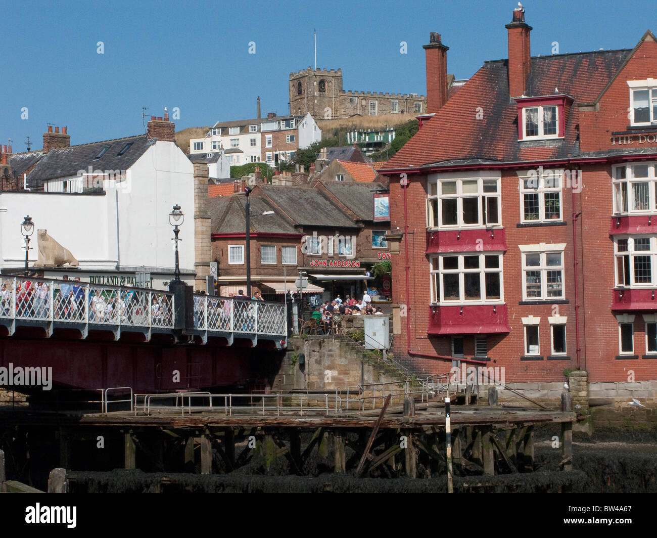 People crossing a swing bridge with St Mary's Church in the background ...