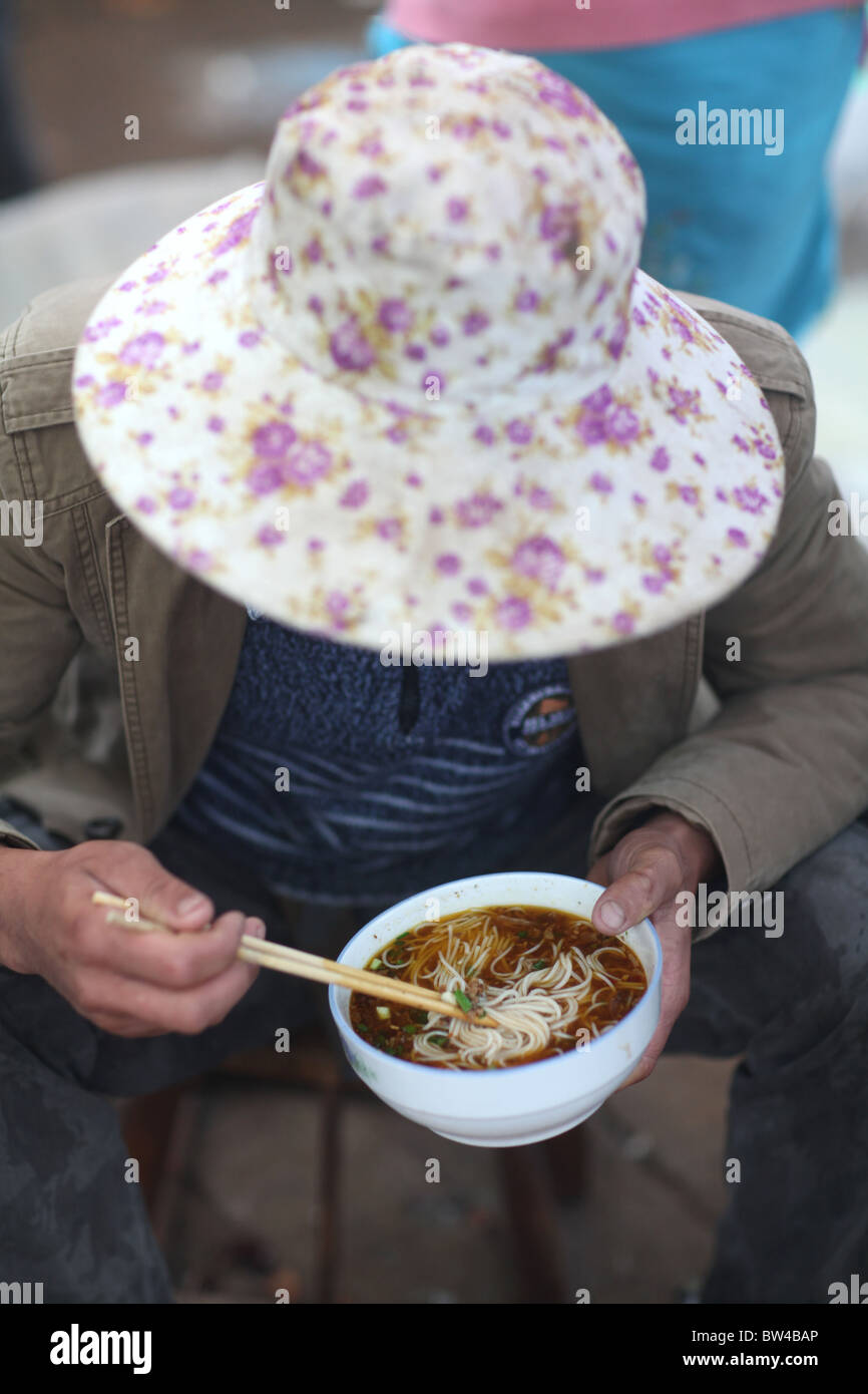 A woman eating noodles in the Bulang Shan Mountain area of Menghai ...