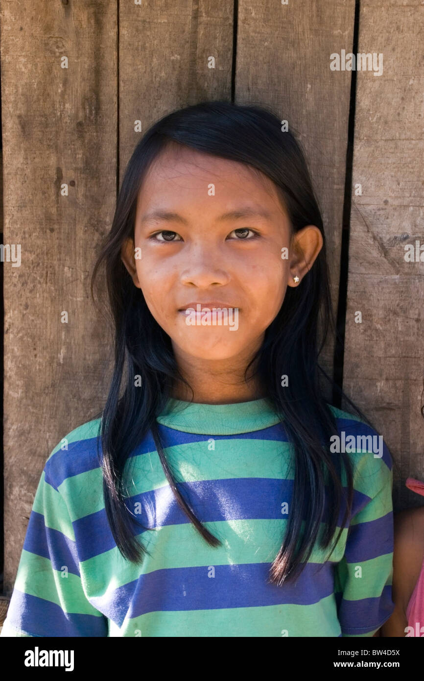 A young girl living in poverty poses for a portrait at her wood home in ...