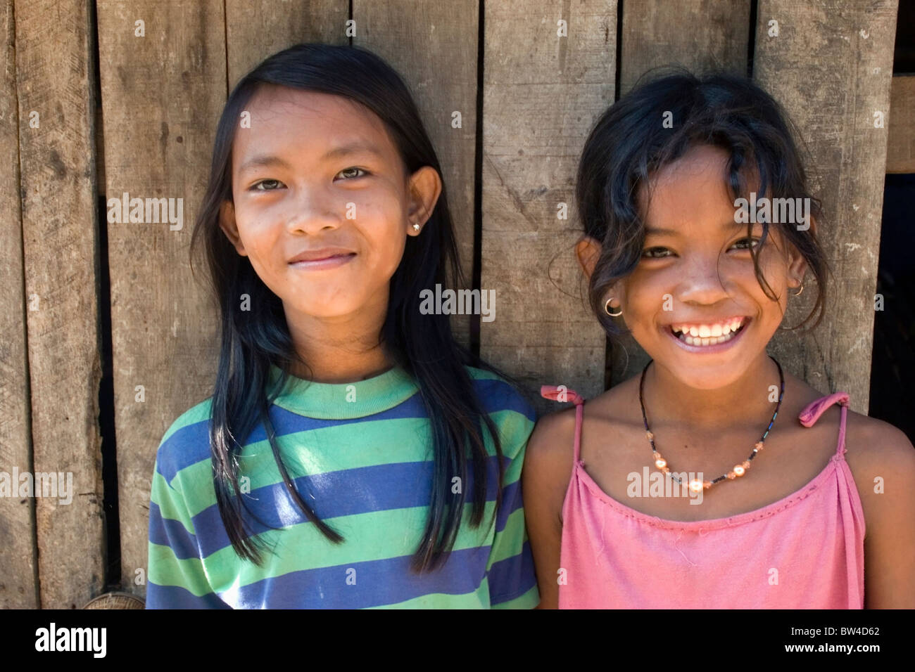 Two happy young girls living in poverty are smiling at their home in ...