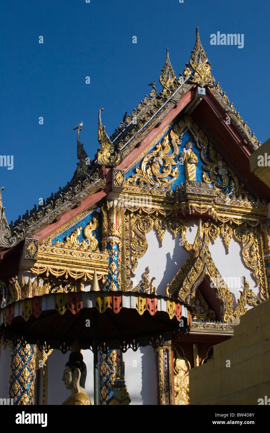 A bright Buddhist temple decorated with ornate designs is part of the ...