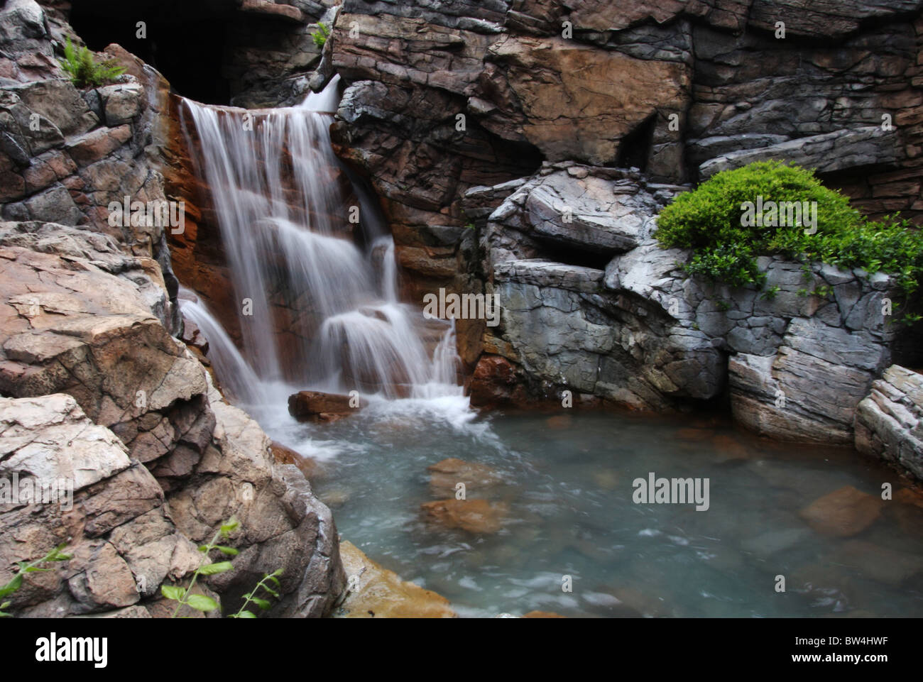 A waterfall over rocks taken with a slow shutter speed to cause the ...