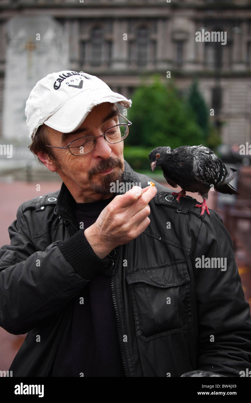 man feeding wild pigeons in George Square, Glasgow Stock Photo - Alamy