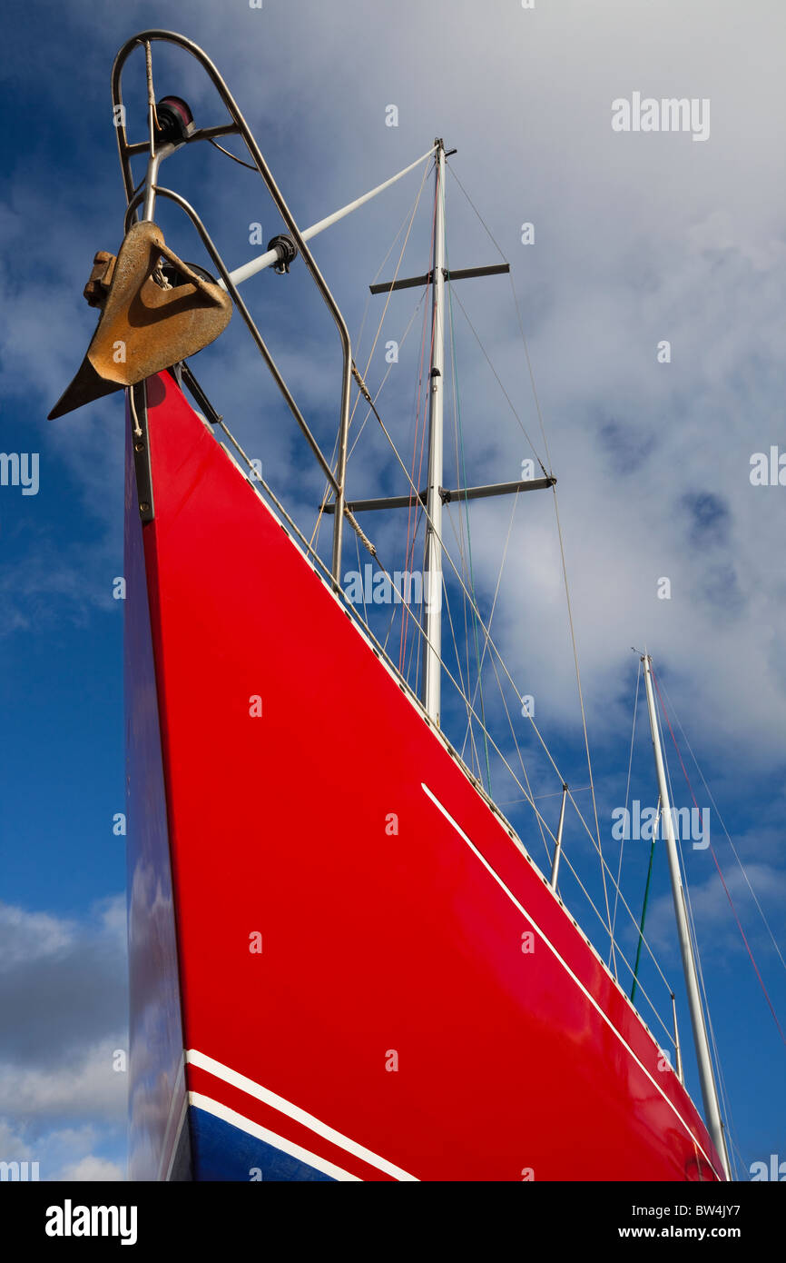Red and blue hull of a yacht against a blue sky with clouds while the ...
