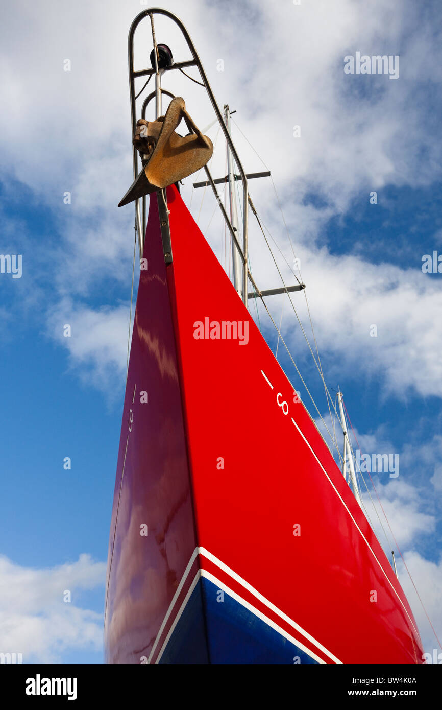 Red and blue hull of a yacht against a blue sky with clouds, boat in ...