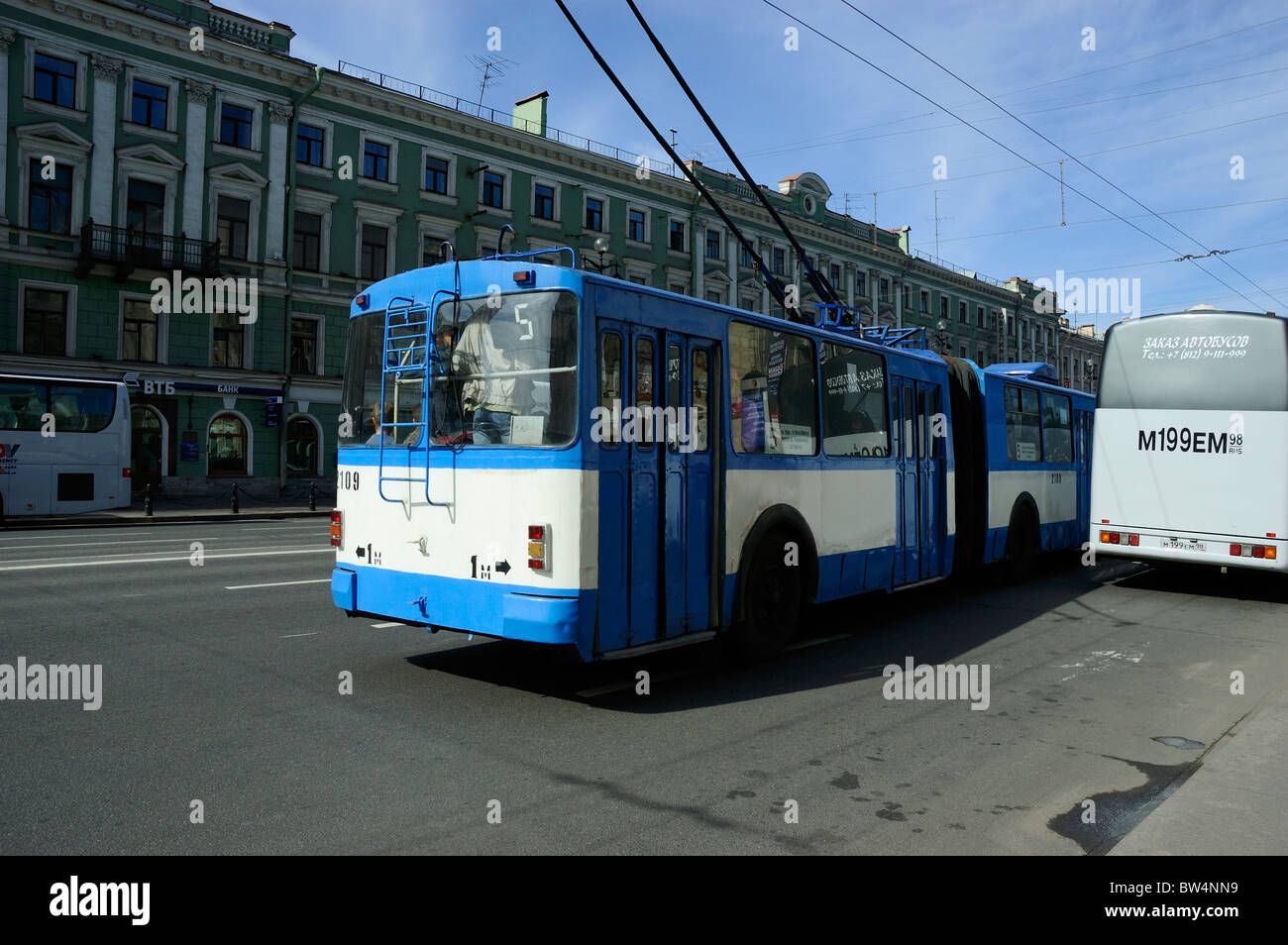 A blue and white Trolleybus passes a stationary coach in St Petersburg ...