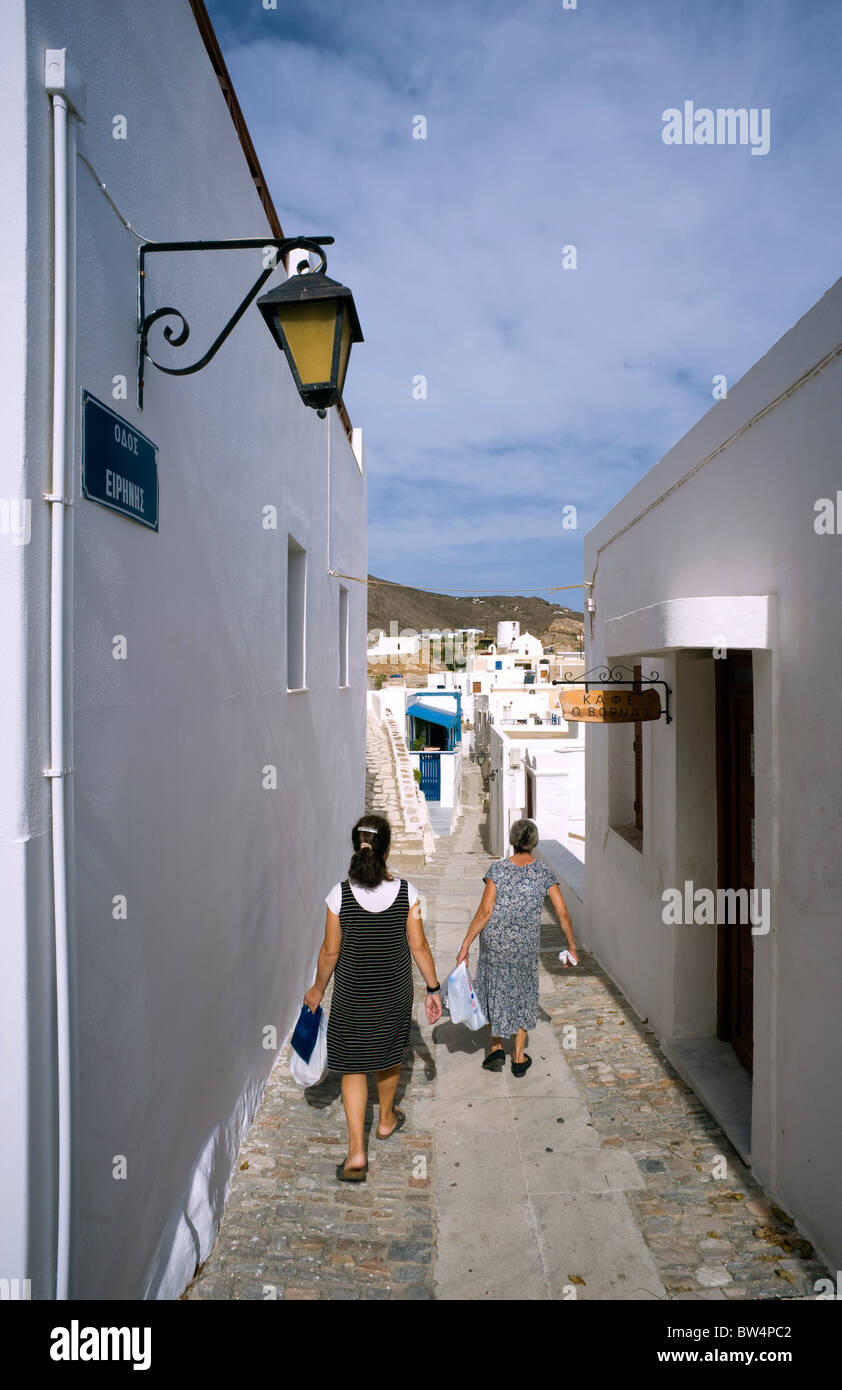 Two women carrying grocery bags are walking on a typical narrow street ...