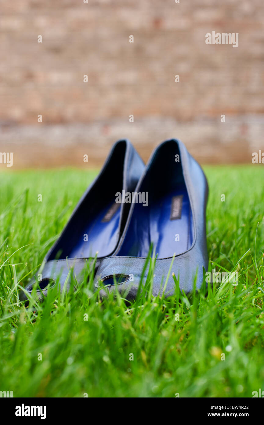 Dark blue women's high heels with a peep hole in the toe on a green ...