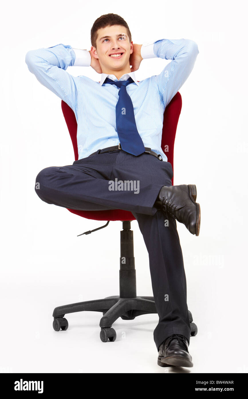 Portrait of positive man relaxing in arm-chair with hands behind head ...