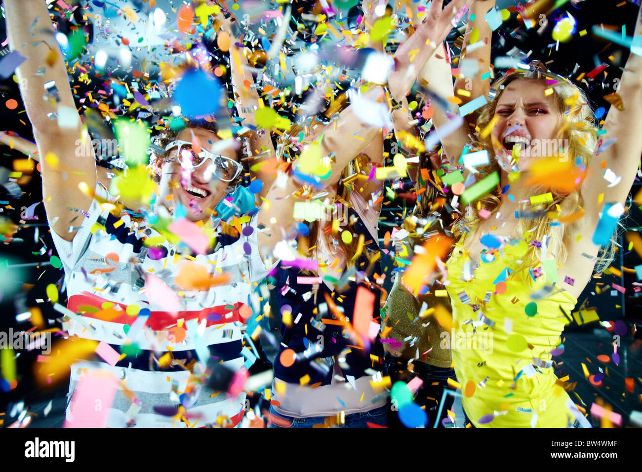Photo of excited teenagers in confetti raising their arms expressing ...