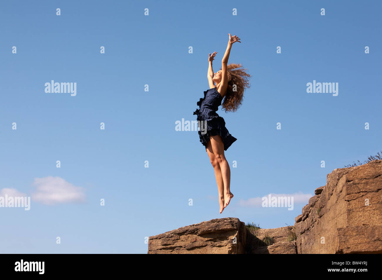 Photo of delighted female leaping over rocky cliff in excitement Stock ...