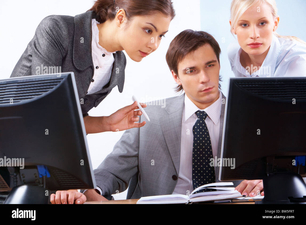 Serious business people looking at computer screen during corporate ...