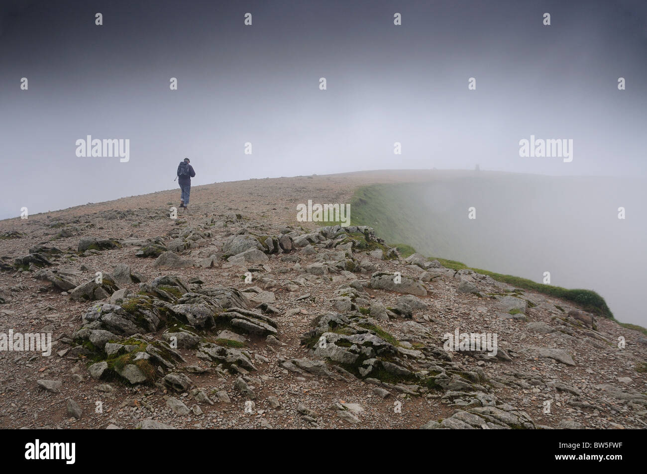 Walker in the mist on the summit of Helvellyn in the English Lake ...