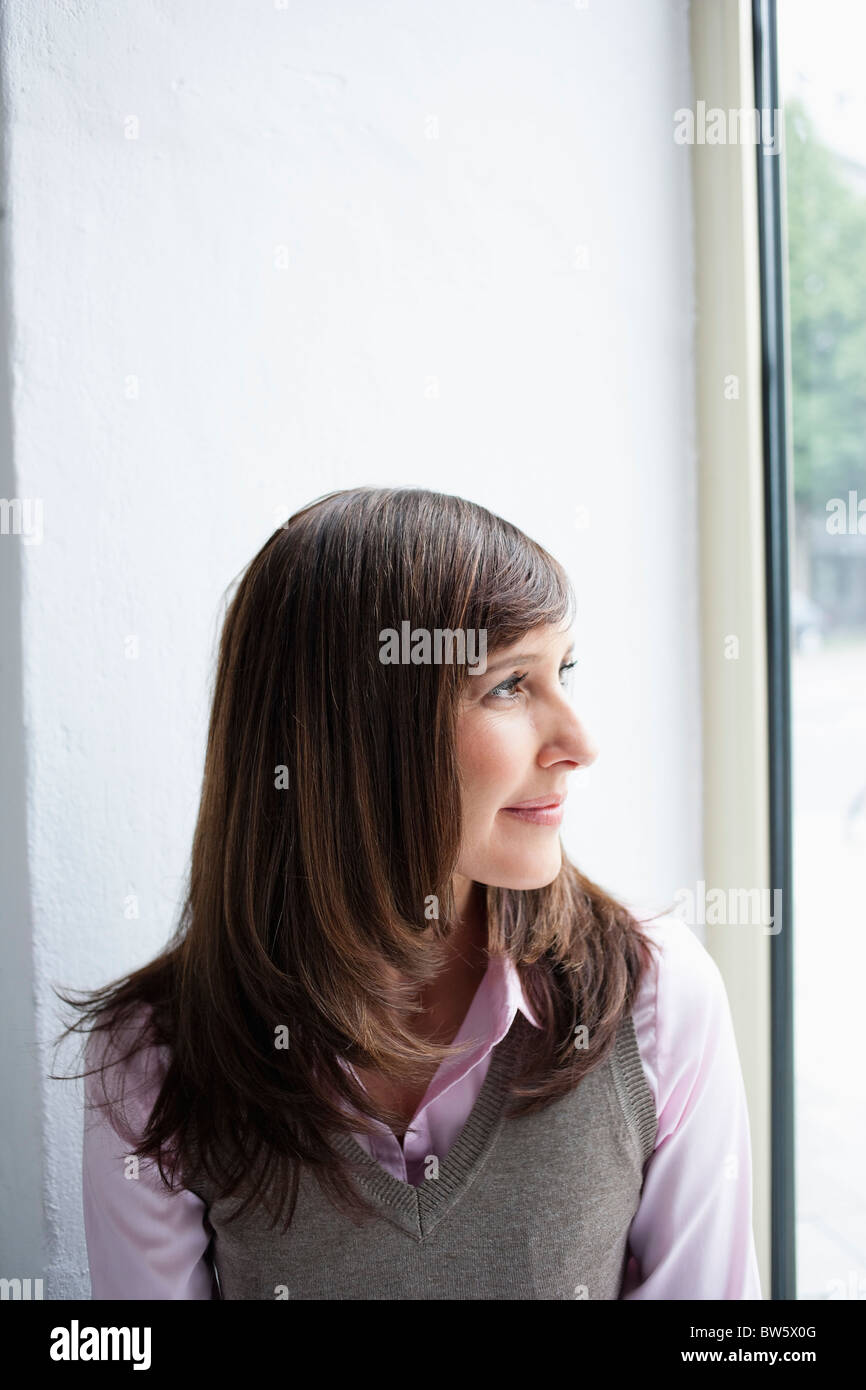 Woman looking out window portrait Stock Photo - Alamy