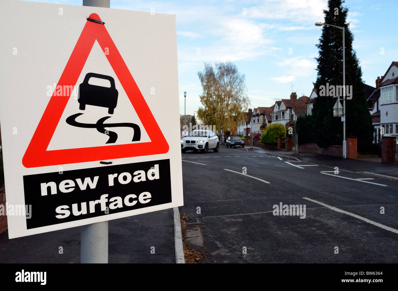 sign warning that new road surface may be slippery Stock Photo - Alamy