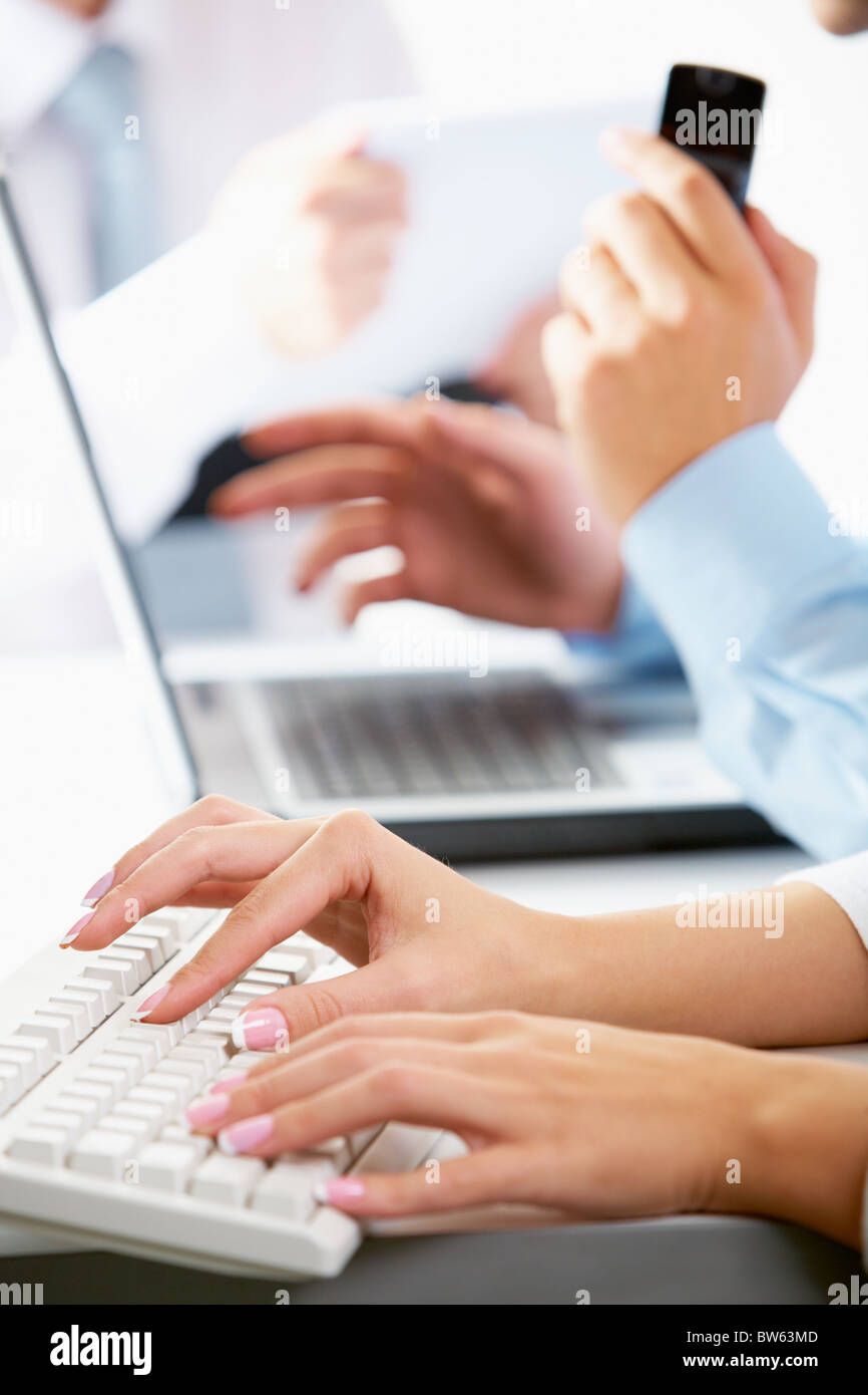 Vertical image of female hands typing a letter in a working environment ...