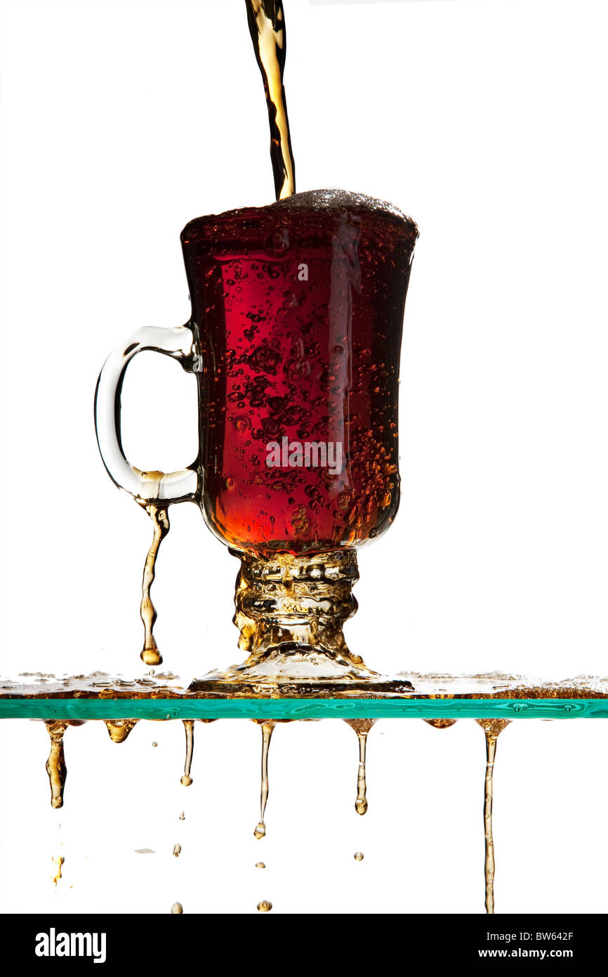 Pouring a cup of coffee, coffee overflowing and spilling onto the table ...