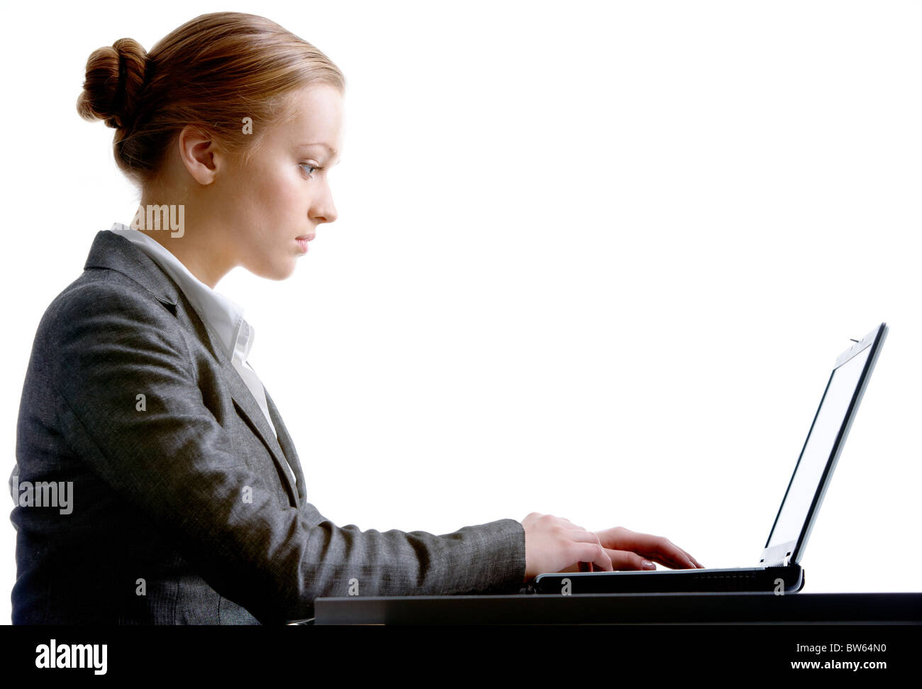 Profile of serious businesswoman typing at workplace over white ...