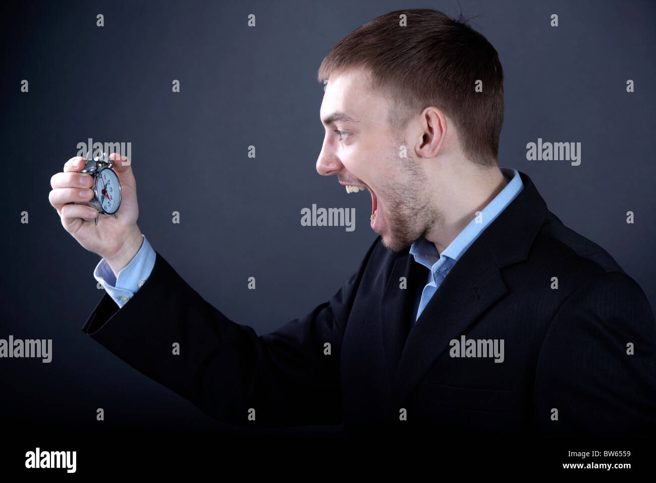 Portrait of young man looking at clock and shouting Stock Photo - Alamy