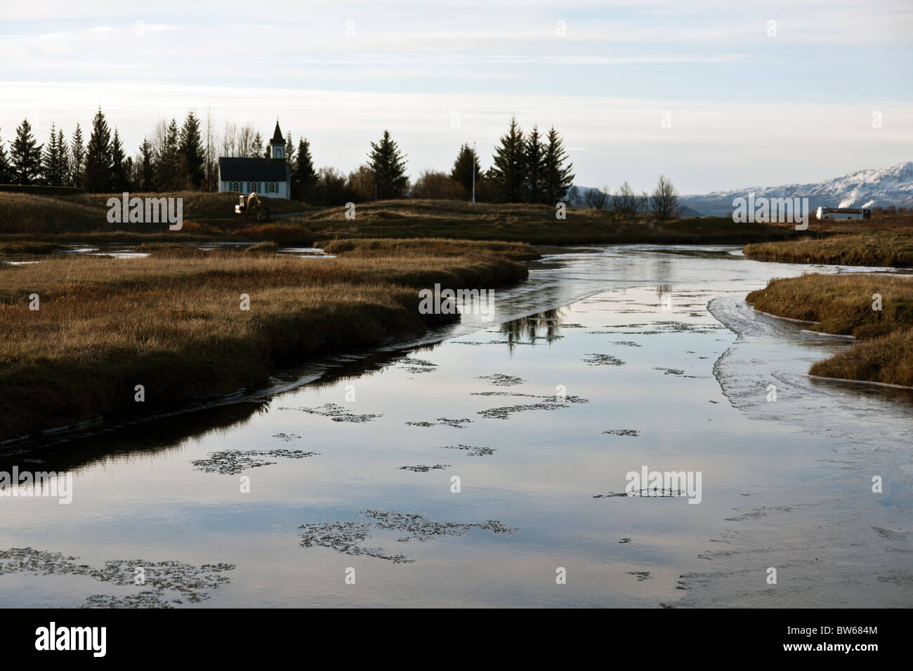 Semi-frozen river Oxara with Thingvalla Kirkja church in the distance ...