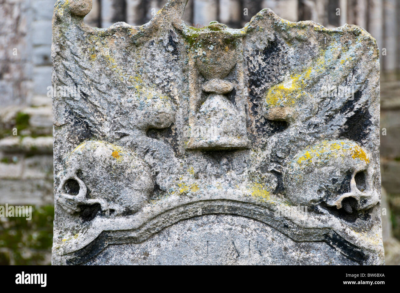 A gravestone carved with winged skulls and an hourglass. LOCATION given ...