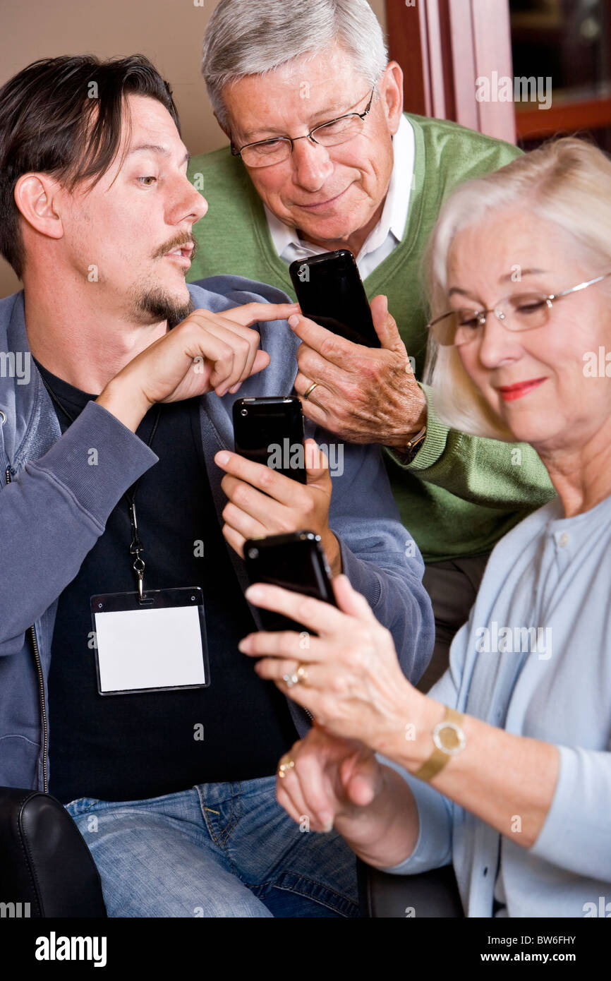 Man helping senior couple use their smart phones Stock Photo - Alamy