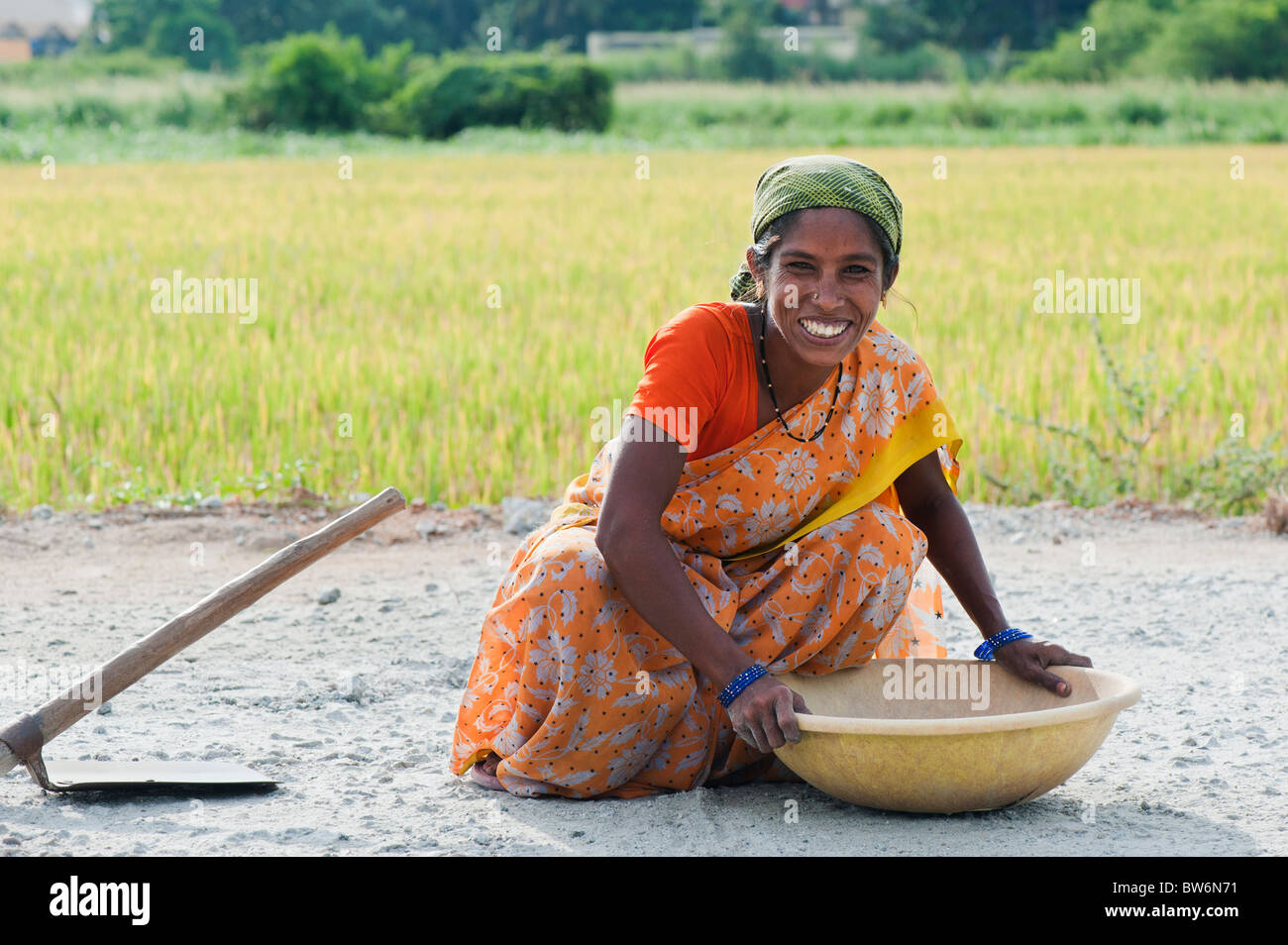 Indian woman road worker picking up stones by hand off a newly laid ...