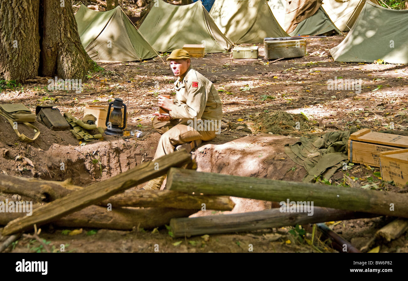 British army soldier sitting on the wooden log camp acting open air ...