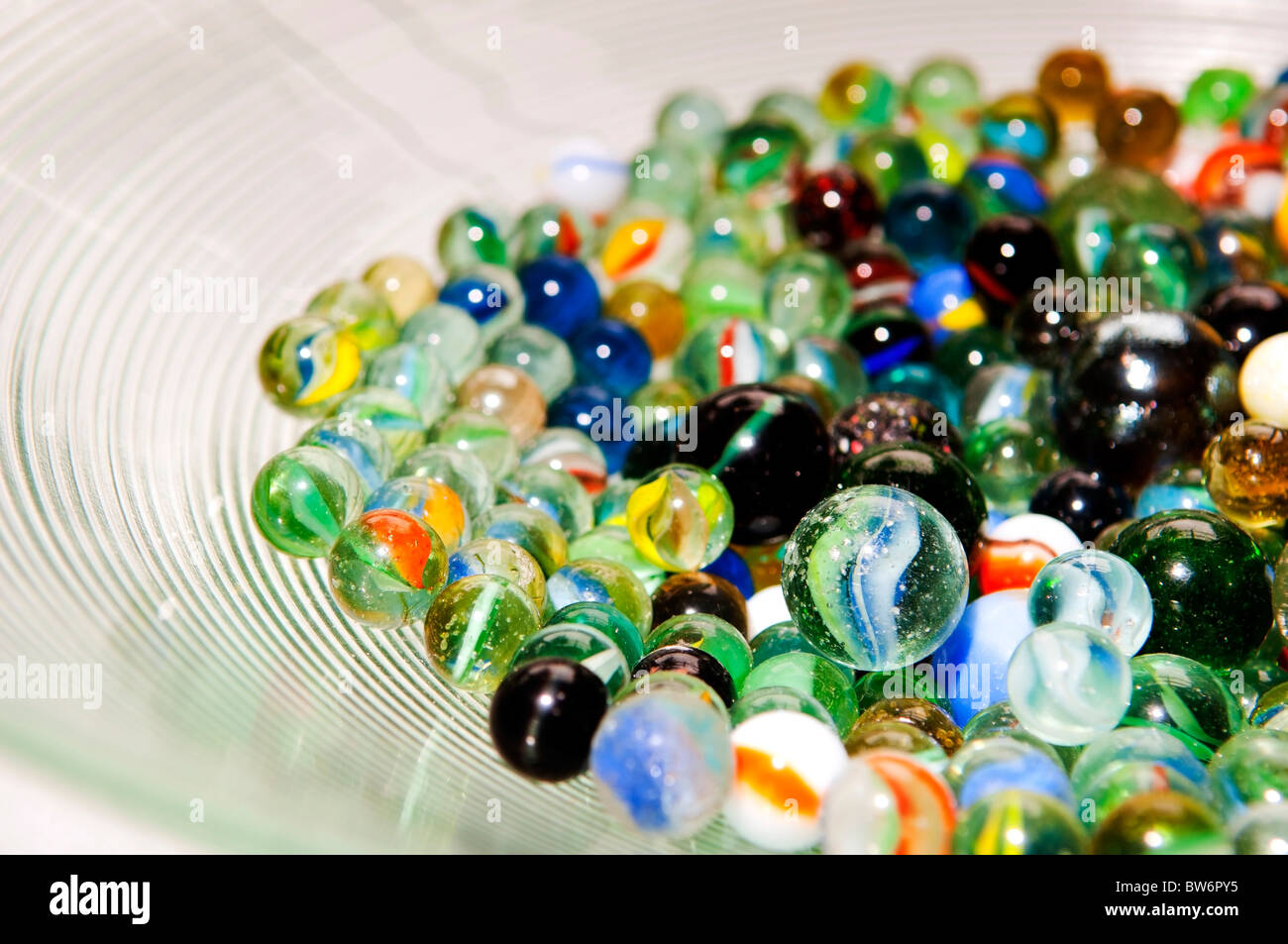 Brightly colored marbles in different shades in a bright glass bowl ...