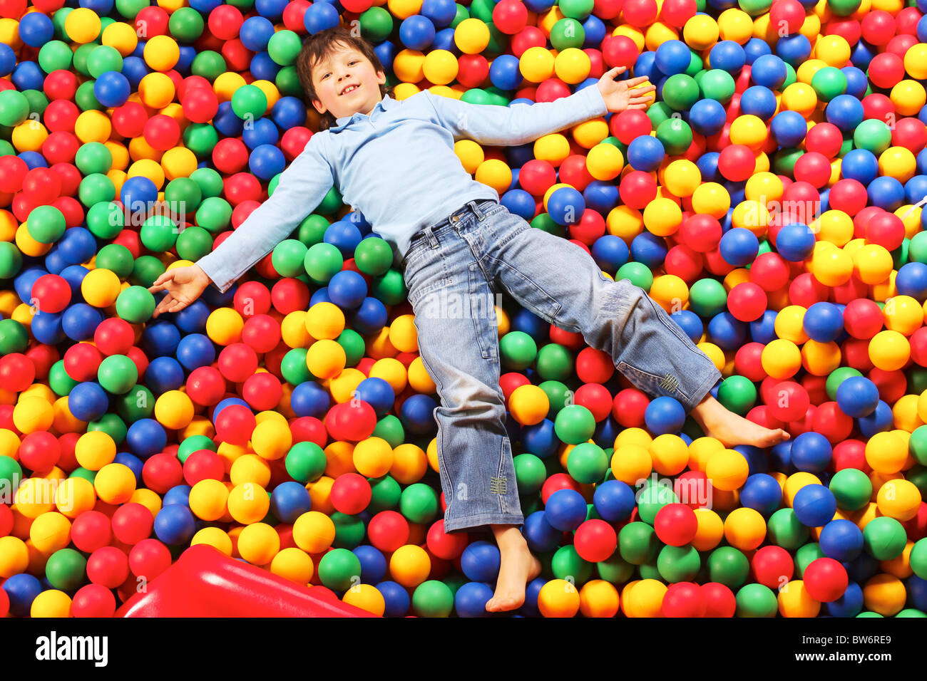 Happy lad seated on colorful balls and looking at camera with smile ...