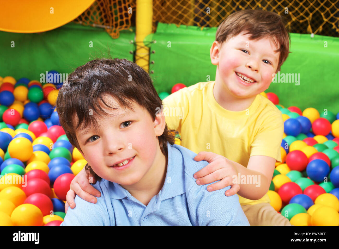 Happy lad embracing his brother and both looking at camera with smiles ...