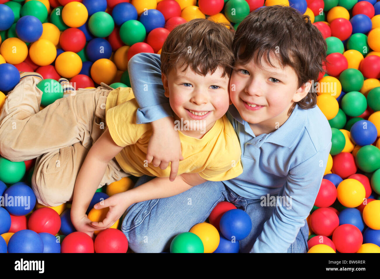 Happy lad embracing his brother and both looking at camera with smiles ...