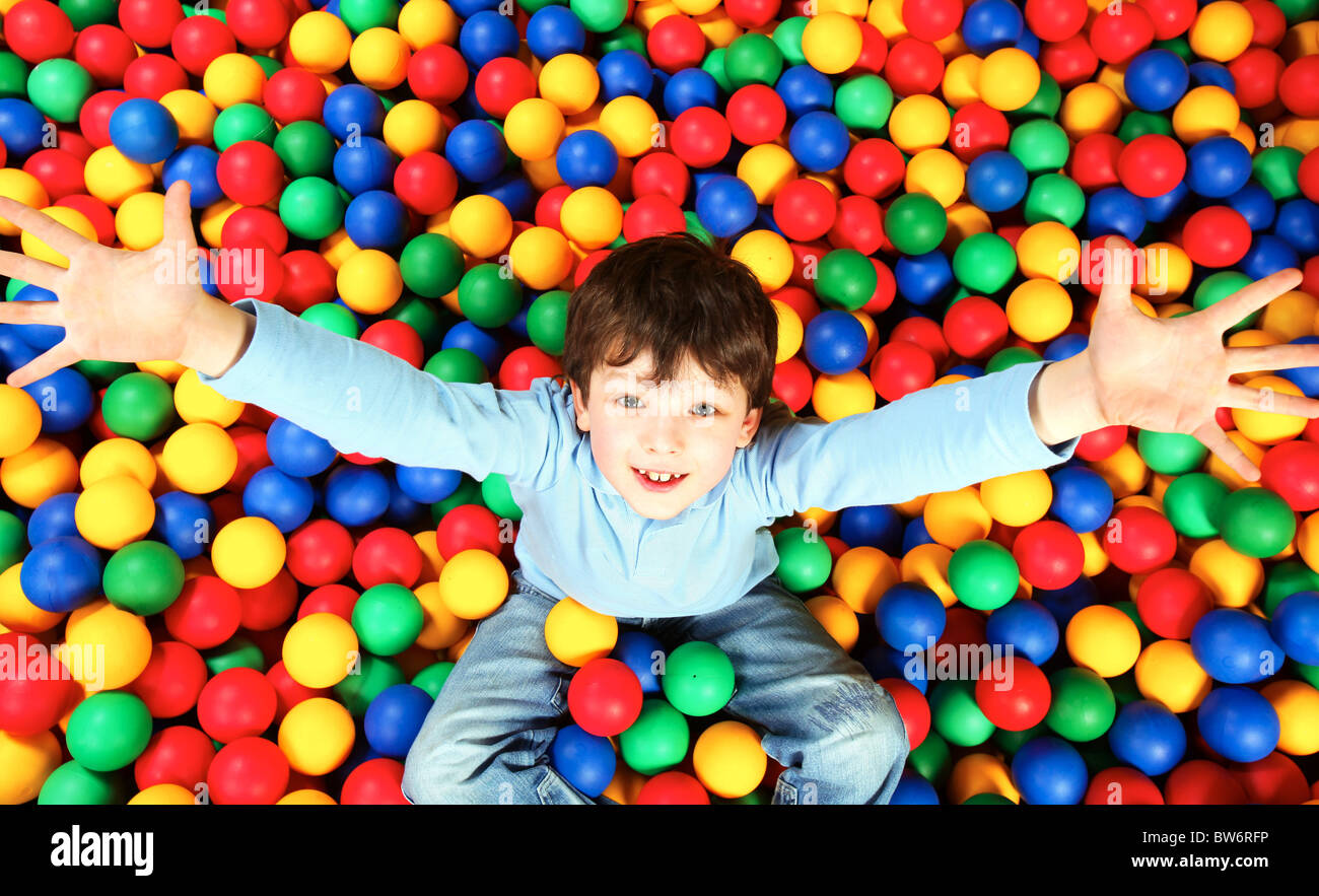 Happy lad seated on colorful balls and stretching arms to camera Stock ...