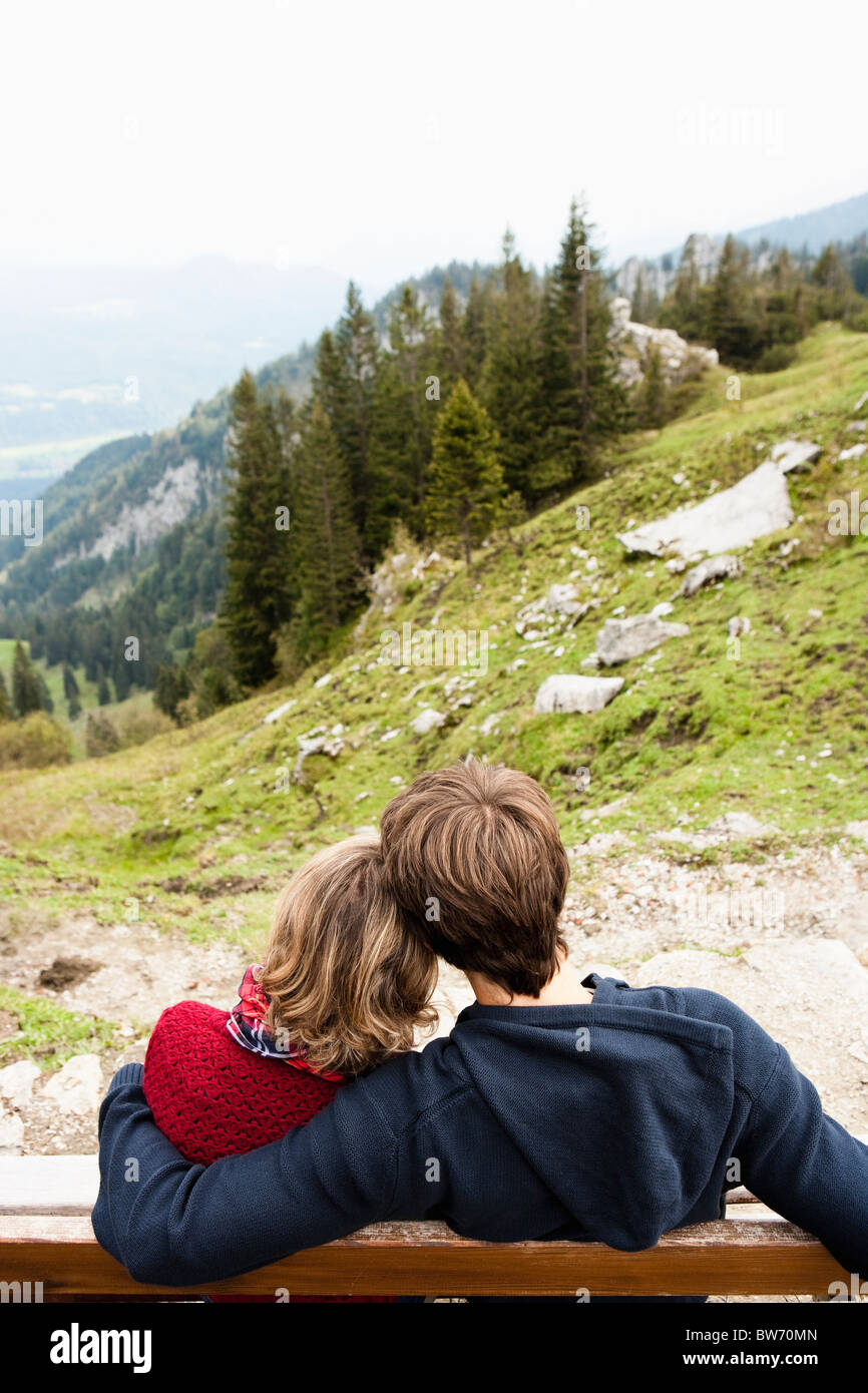 Couple sitting on bench hugging Stock Photo - Alamy