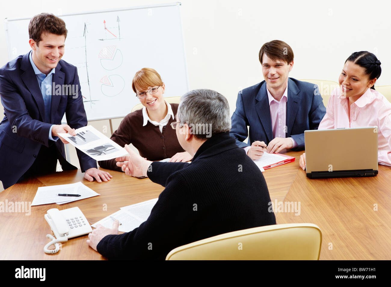 Back view of mature chief passing over paper to employee while the ...