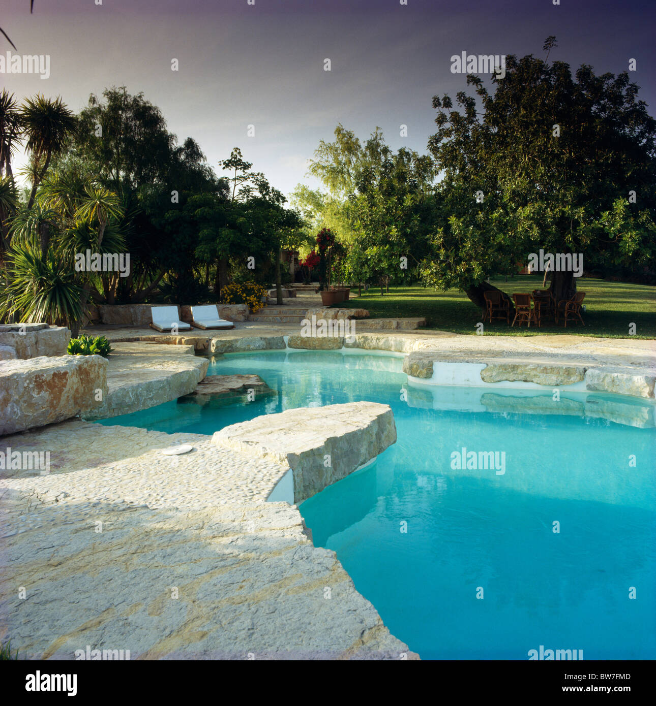 Stone paved edging beside turquoise swimming pool in grounds of villa ...