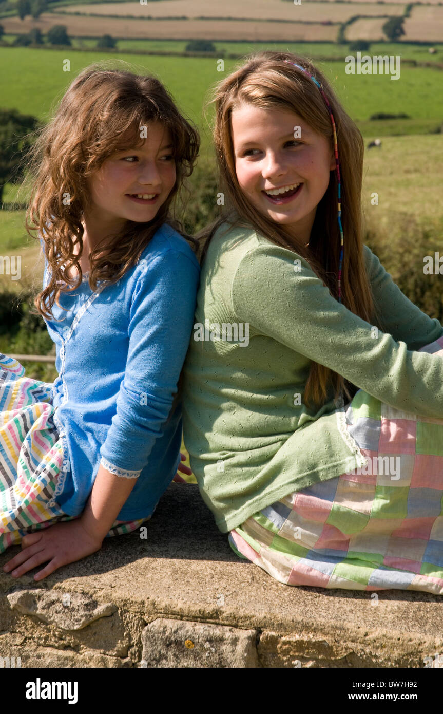Portrait of two girls sitting back to back Stock Photo - Alamy