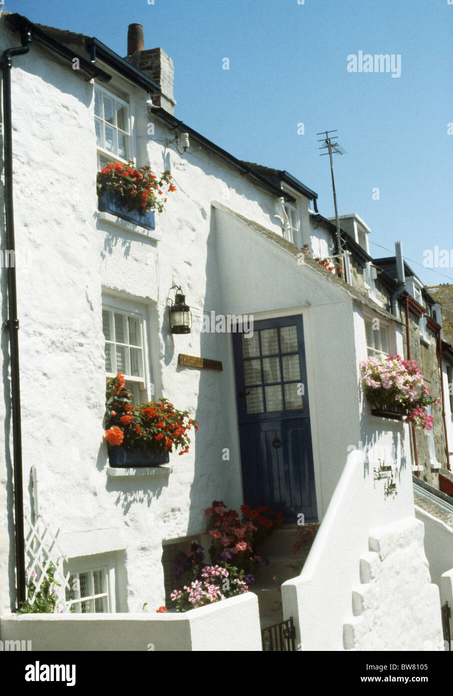 Red geraniums in window-boxes on small white terraced cottage in ...