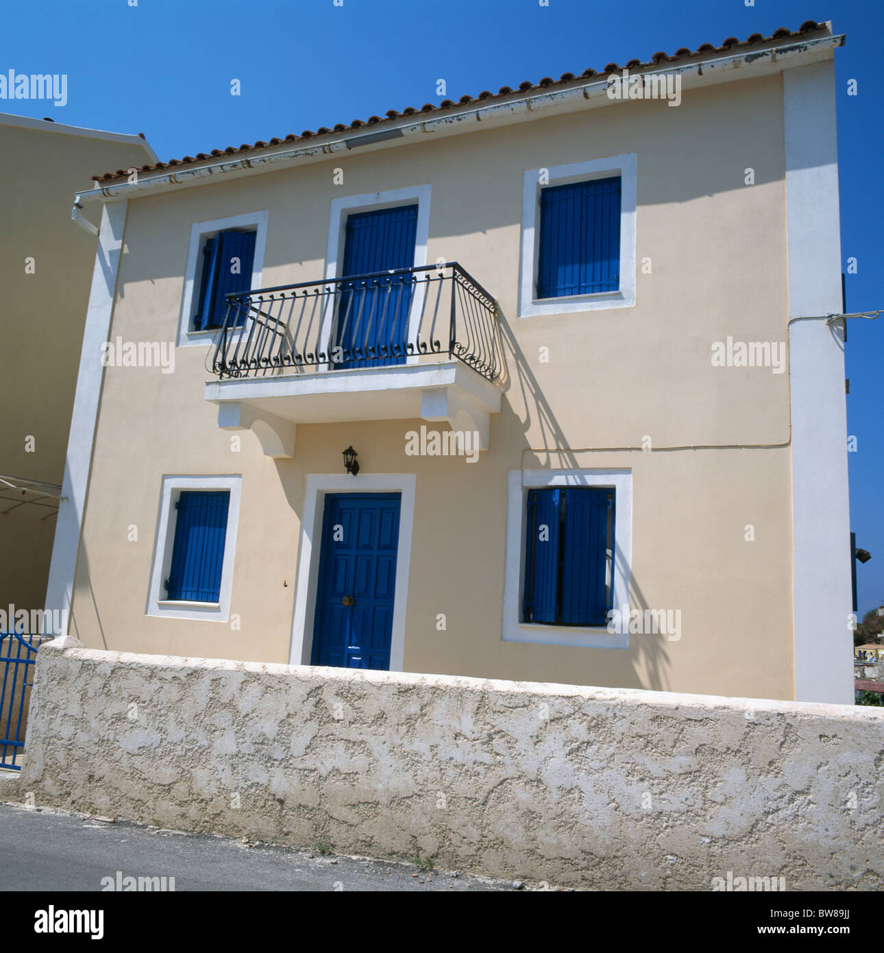 Balcony above front door of newly-built traditional cream painted Greek ...