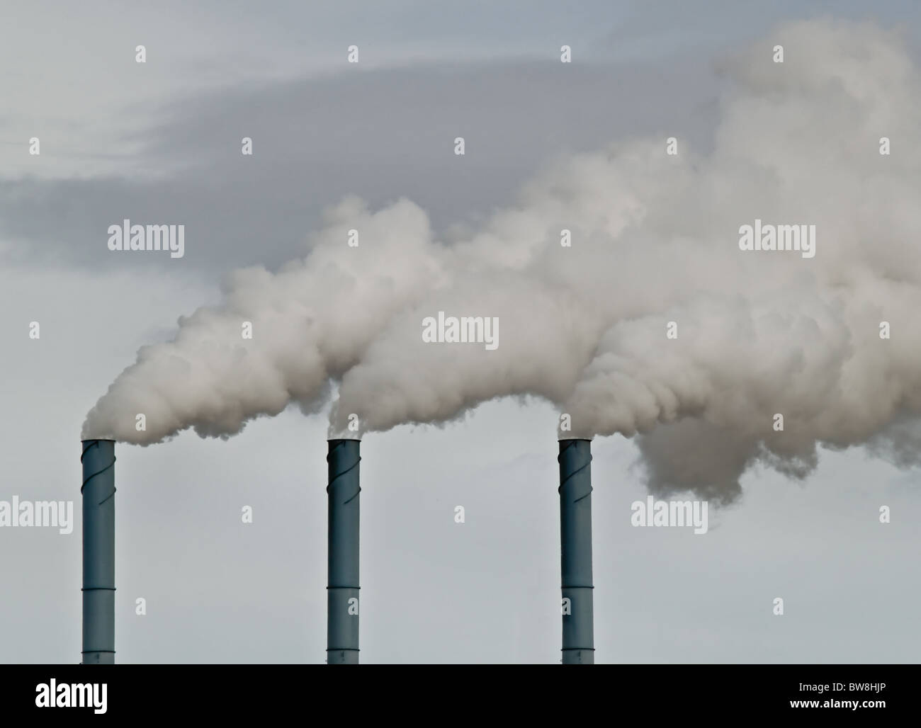 Three industrial factory smokestacks spew out smoke and pollution into ...