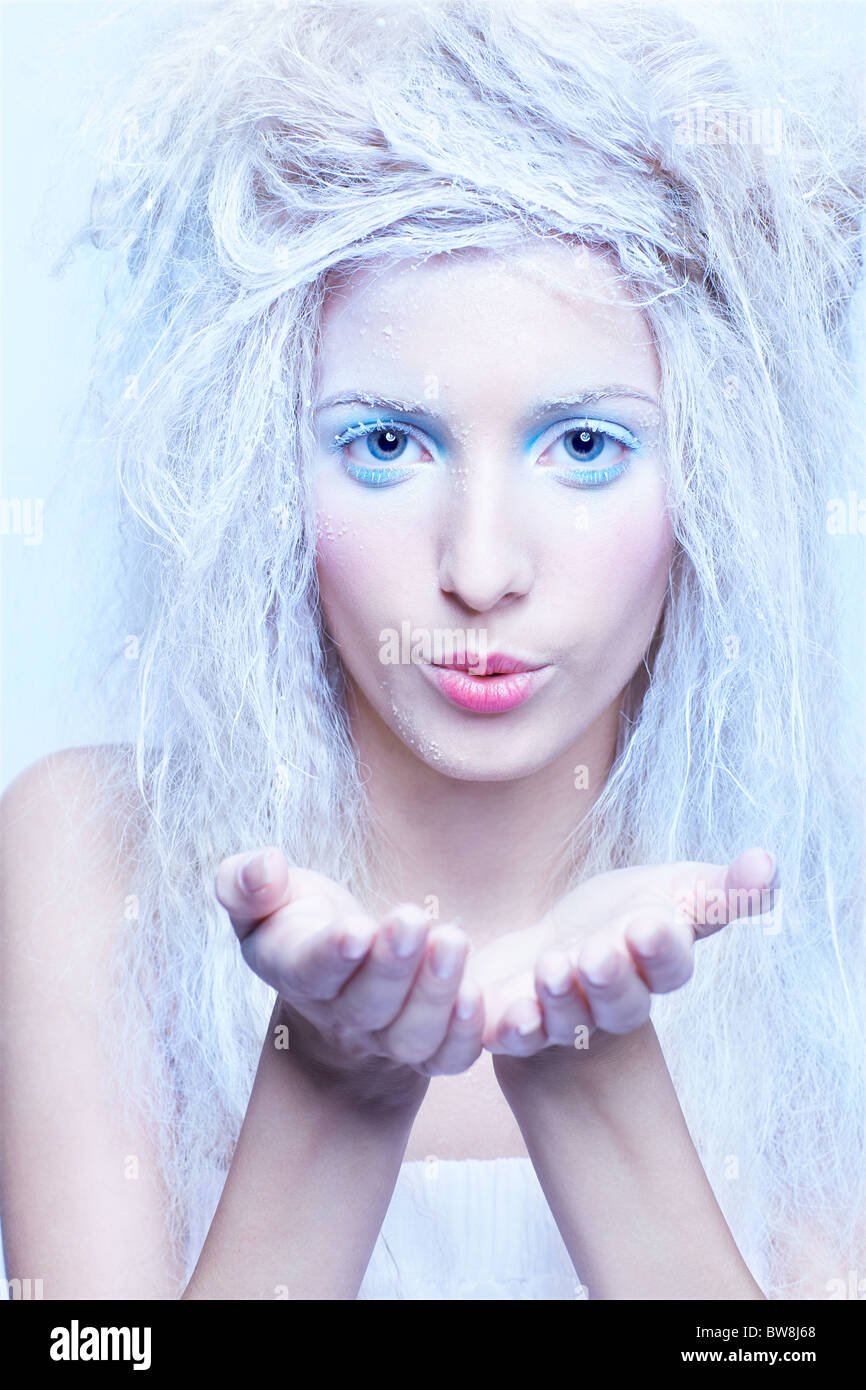 portrait of beautiful blonde frozen fairy girl blowing snow flakes from ...