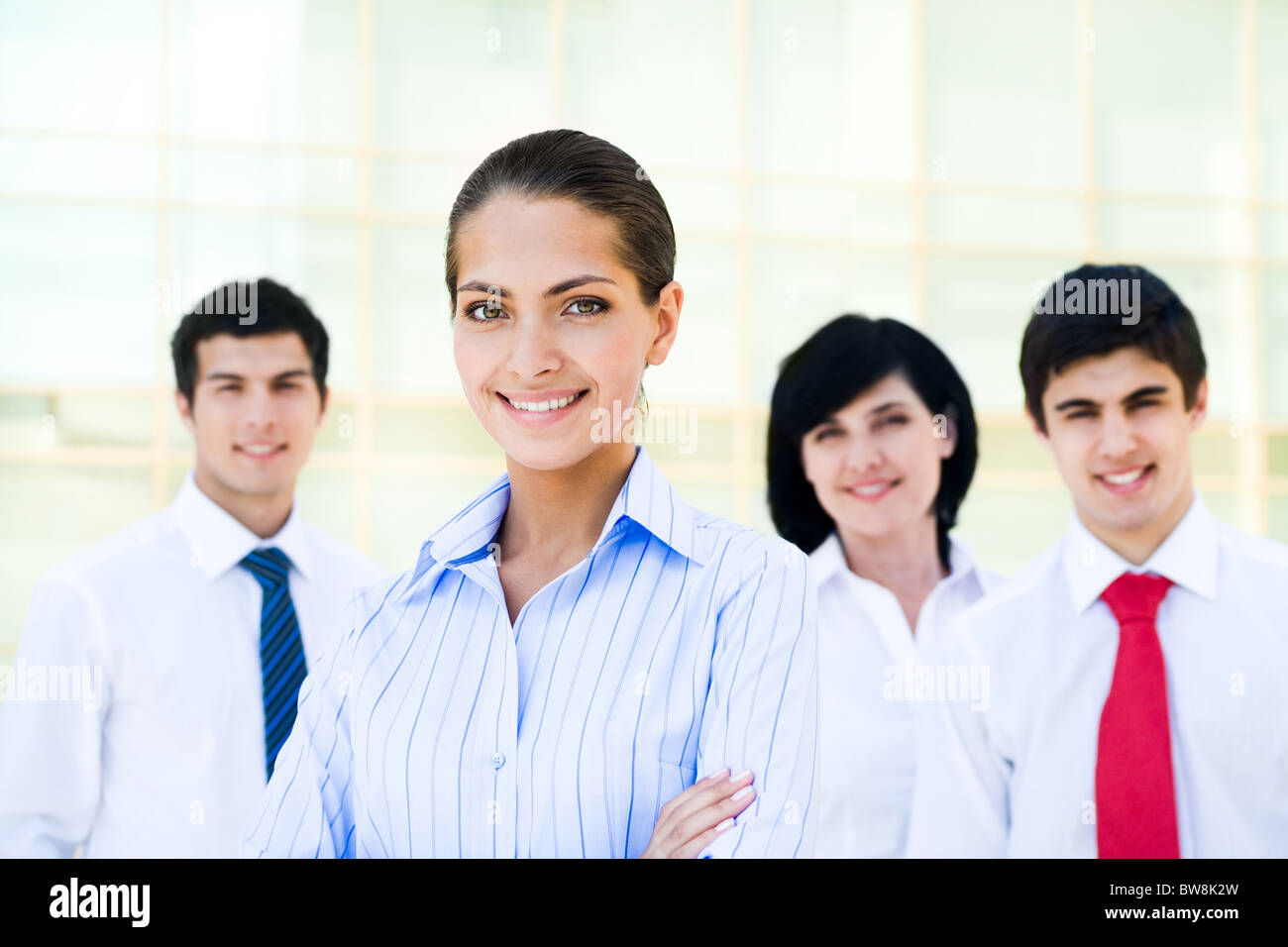 Portrait of pretty employee smiling at camera with business partners at ...