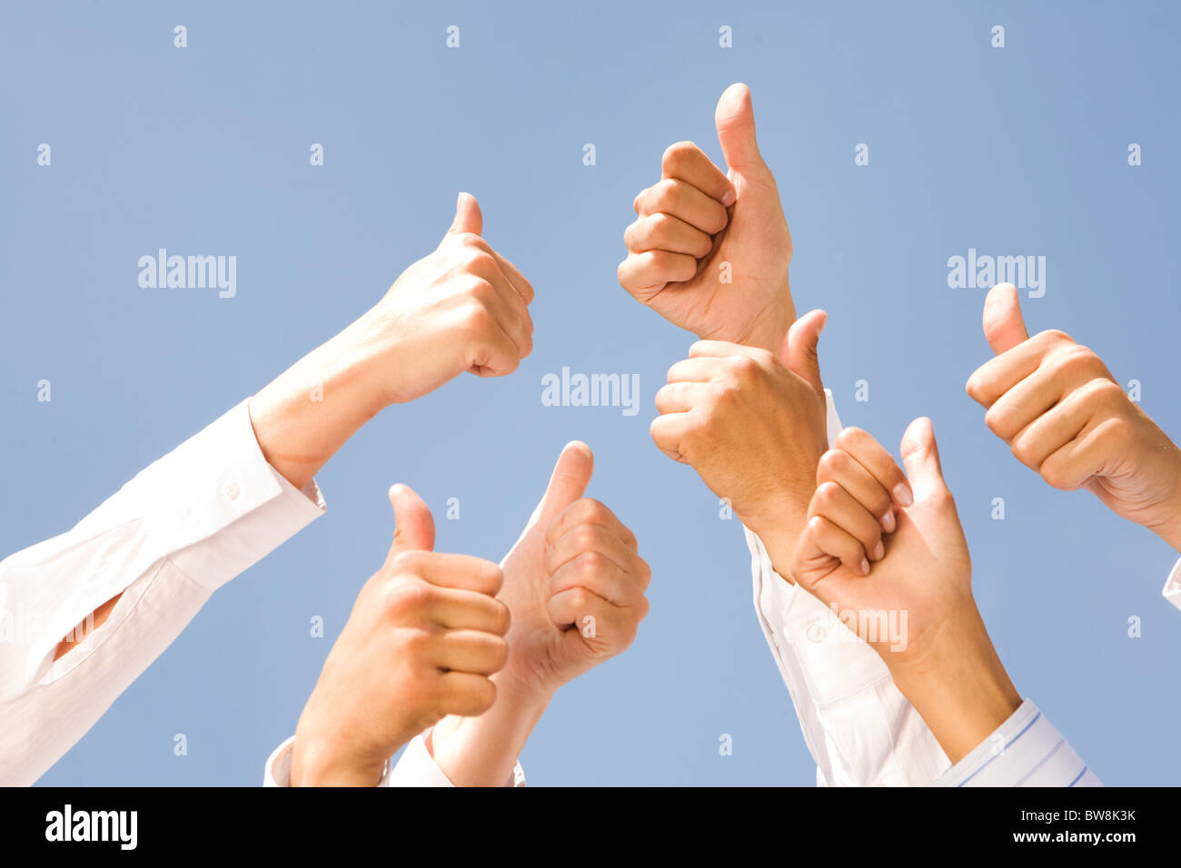 Image of several human hands showing thumbs up against clear blue sky ...