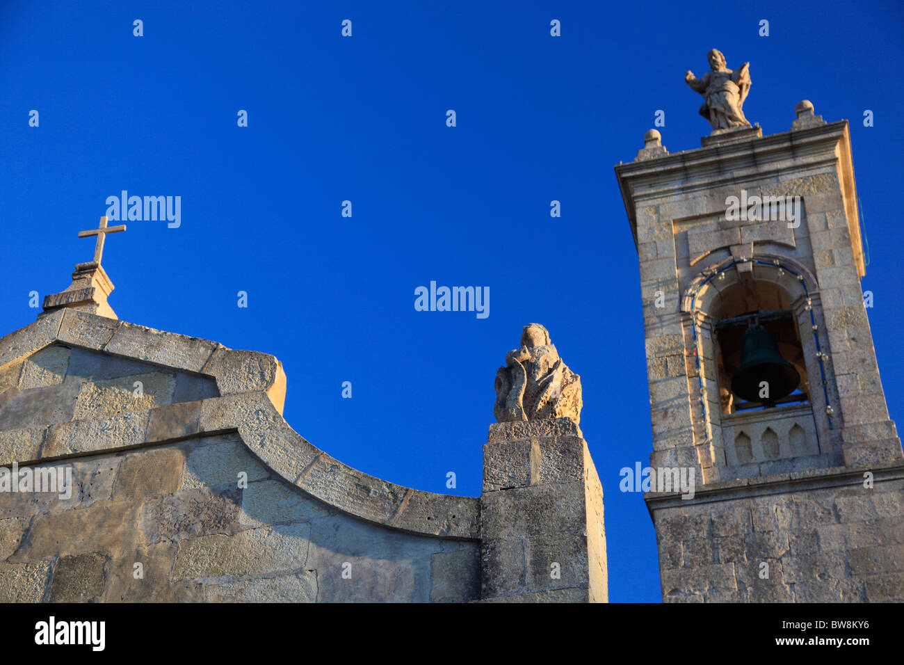 The belltower and part of the facade of old medieval chapel in Gharb in ...
