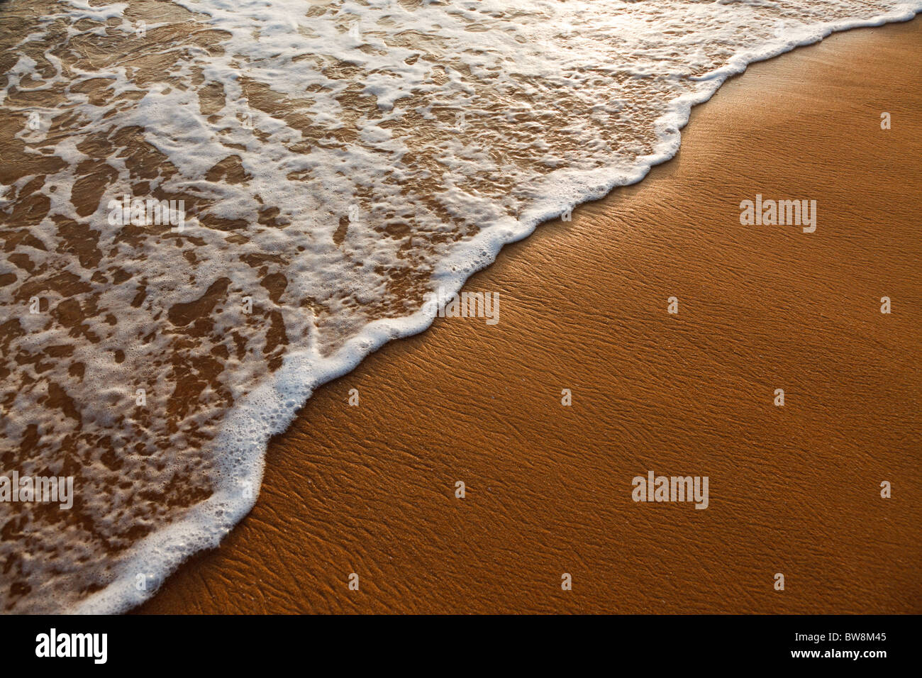 Wave surging on sand on beach Stock Photo - Alamy