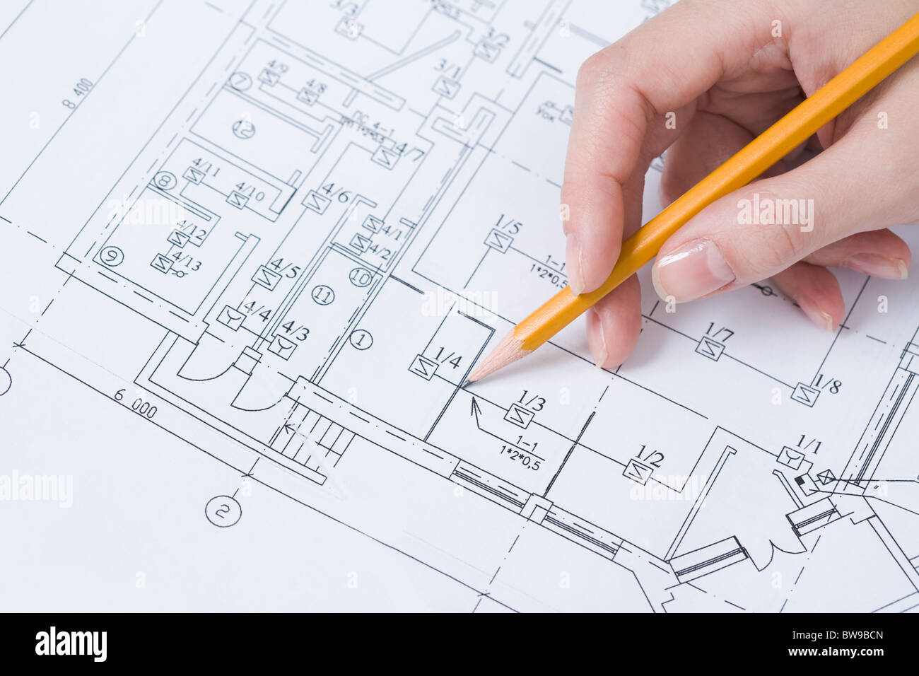 Close-up of human hand with pencil over blueprints with sketches of ...