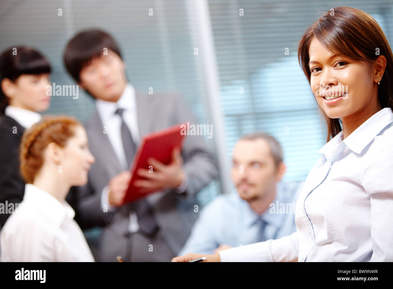 Portrait of smart employer looking at camera on background of people ...